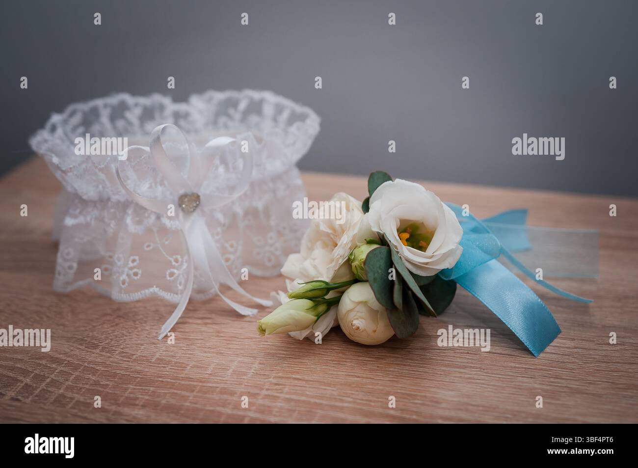 A delicate wedding garter with white lace detailing sits beside a ...