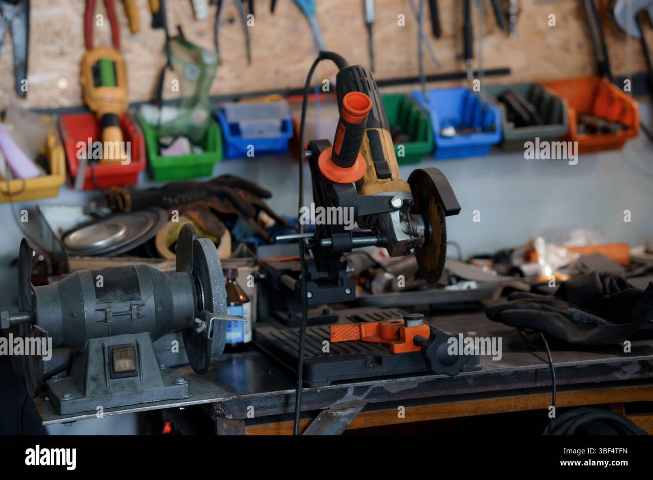 A cluttered workshop scene features two metal grinders on a workbench ...