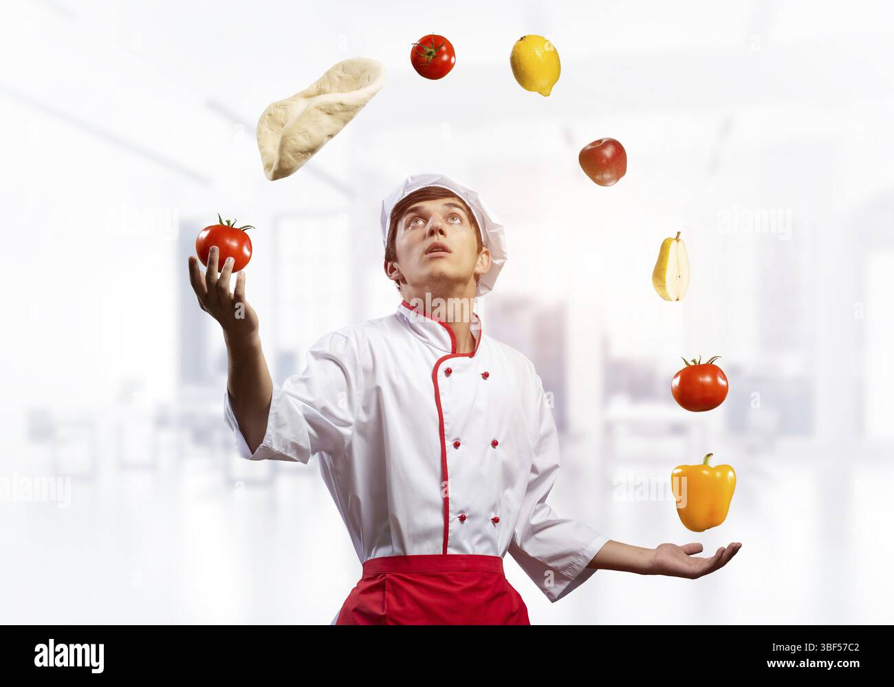 Young male chef juggles with food ingredients. Handsome chef in white ...