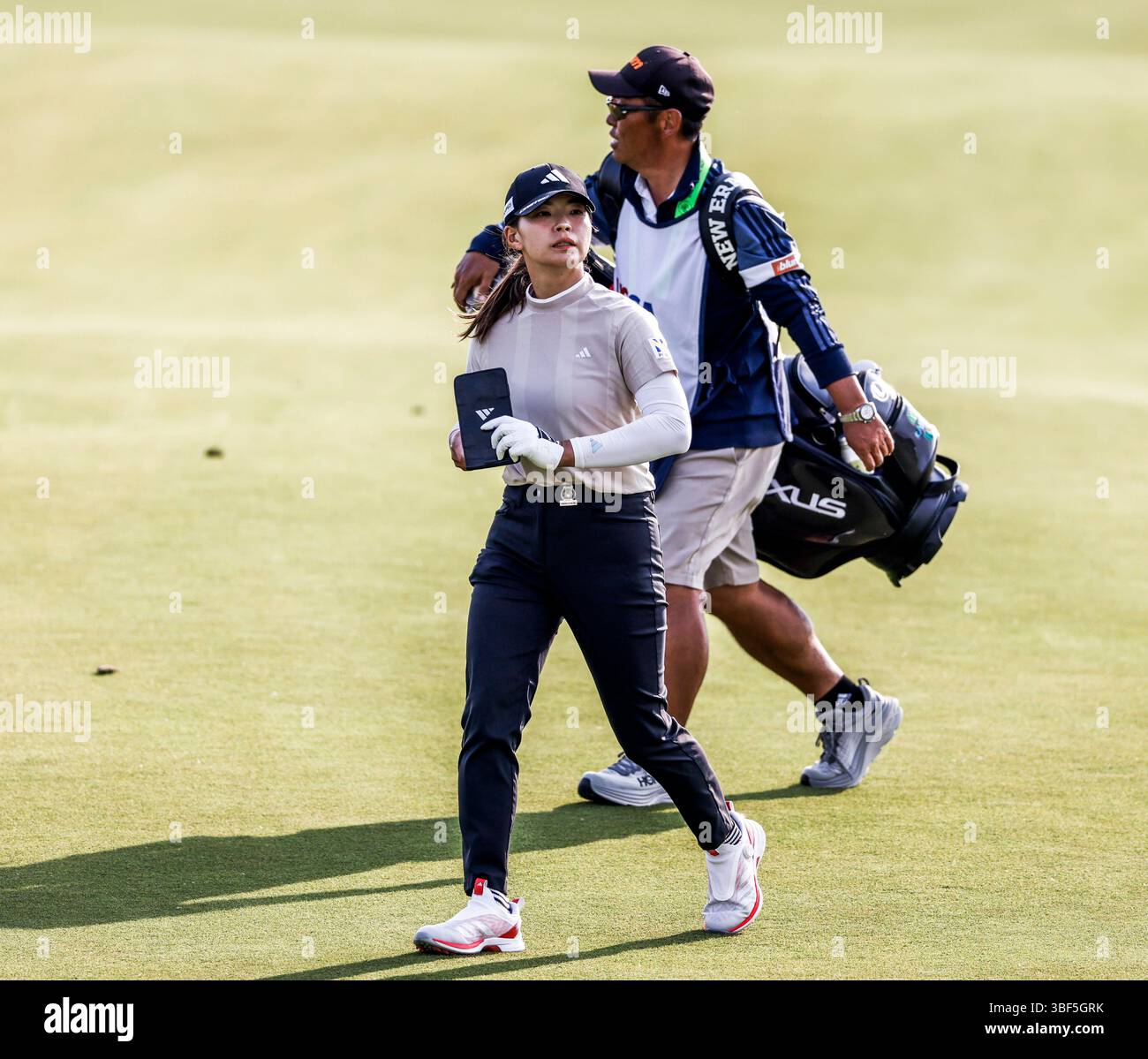 Hinako Shibuno of Japan and caddie Hiroshi Sasaki walk up the 18th fairway during the second ...