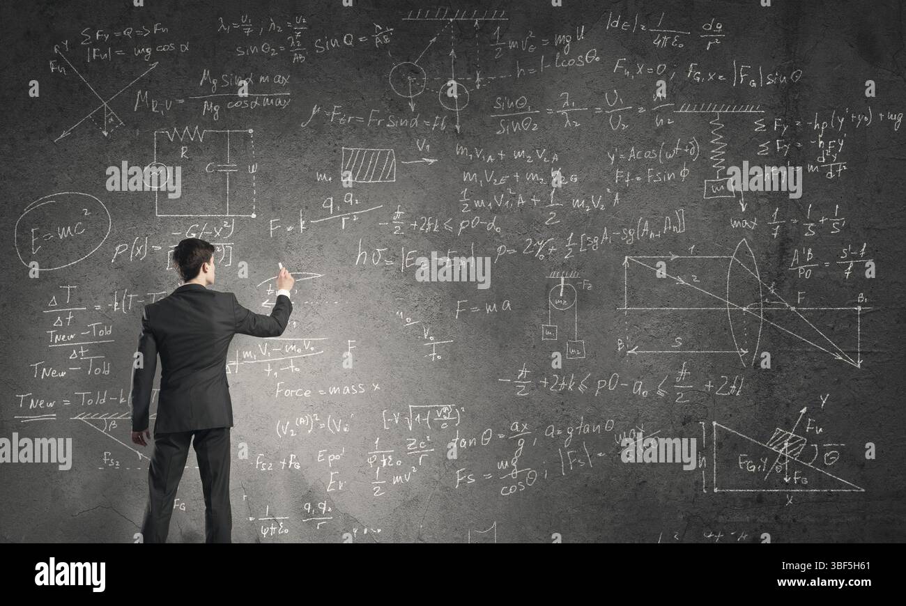 Man in suit standing with back and drawing physics formulas Stock Photo ...