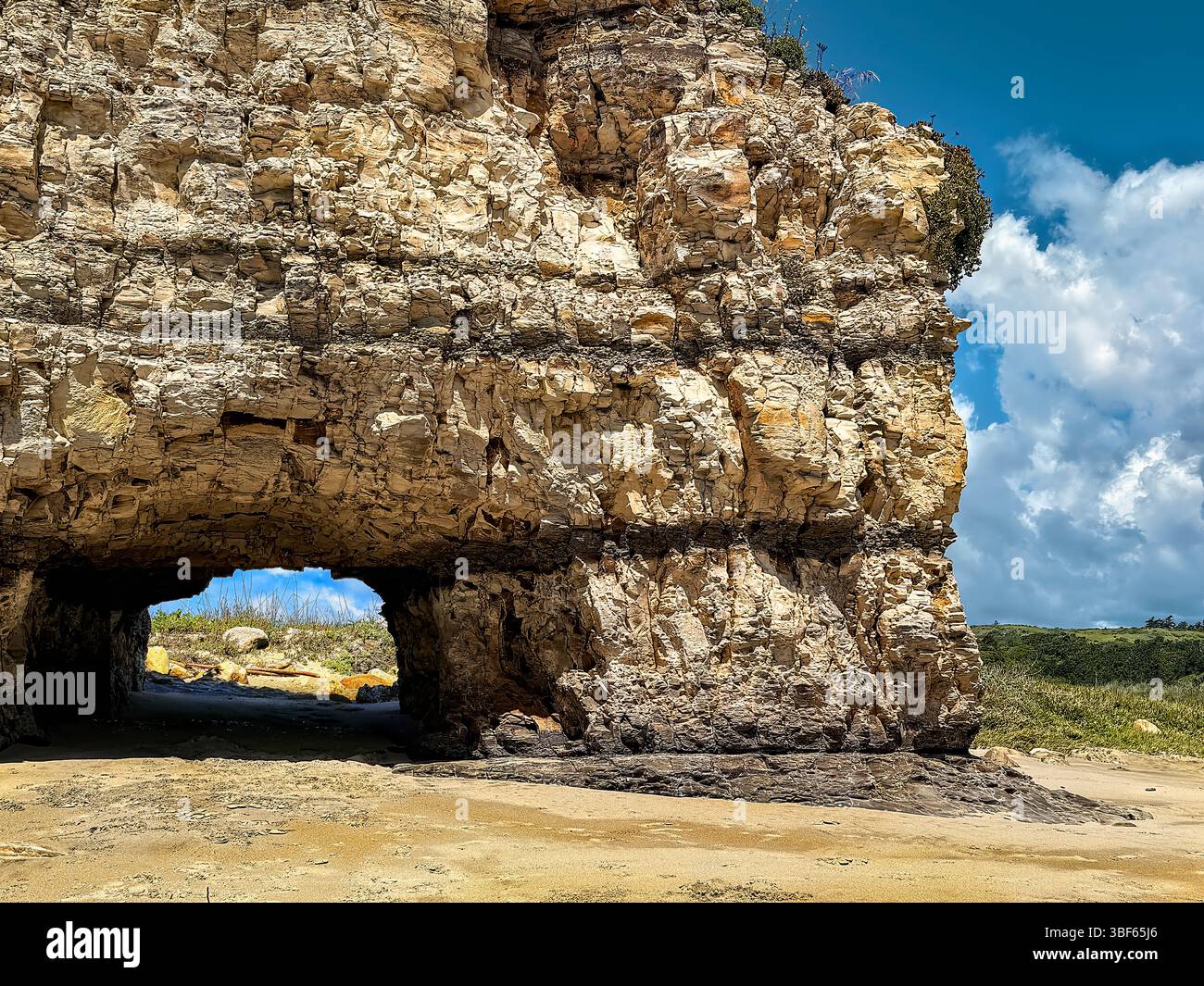 Large cliff with natural arch opening at four mile beach in Santa Cruz ...