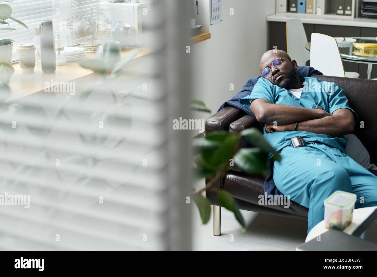 Tired medical professional sleeping in clinic break room, wearing ...