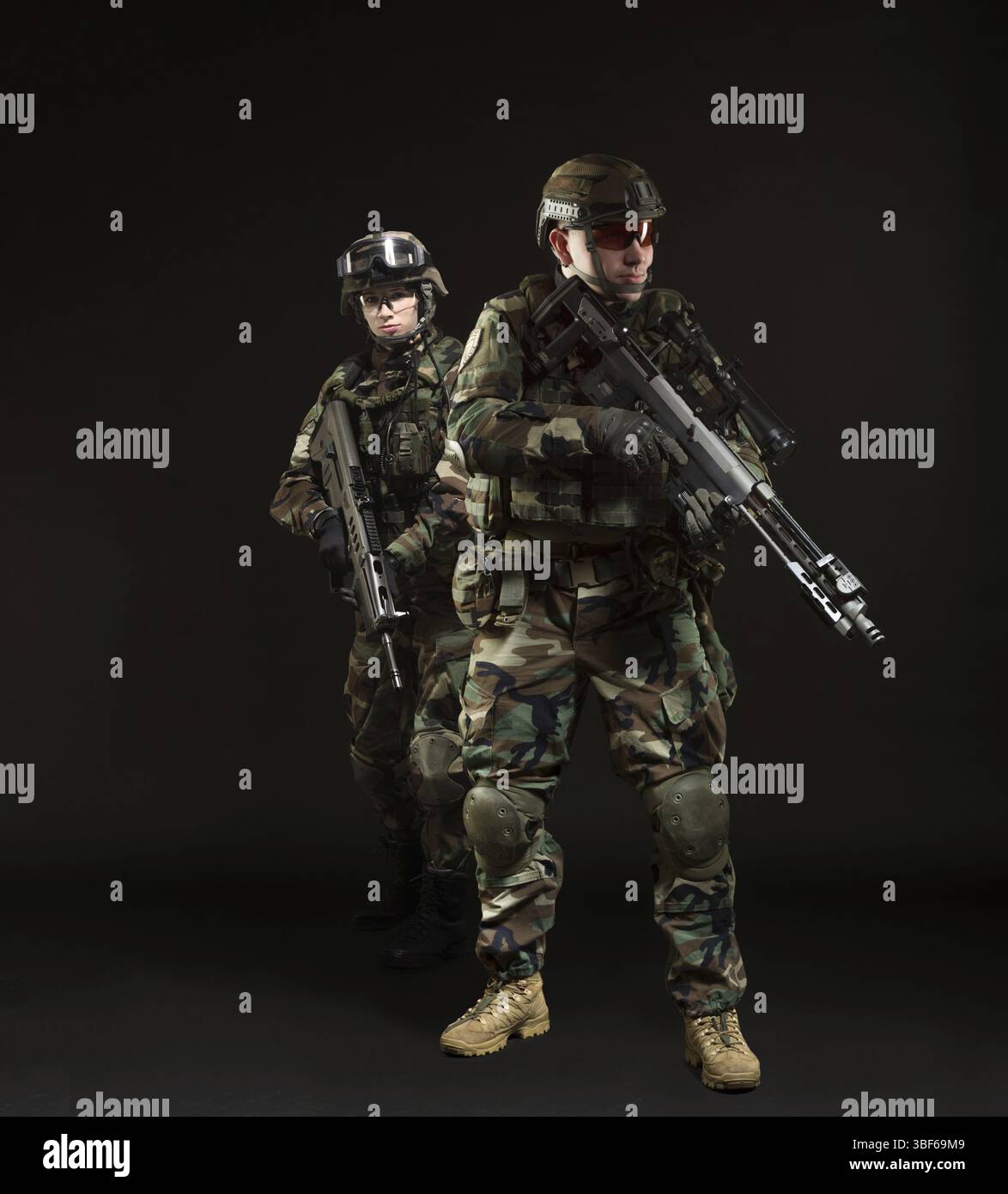 NATO soldiers in full gear. Military man anÐ² woman over black ...