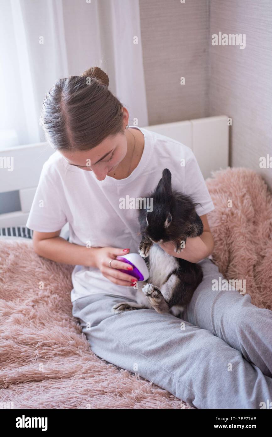 A teenage girl sits on a soft, fluffy bed, lovingly grooming her dark ...