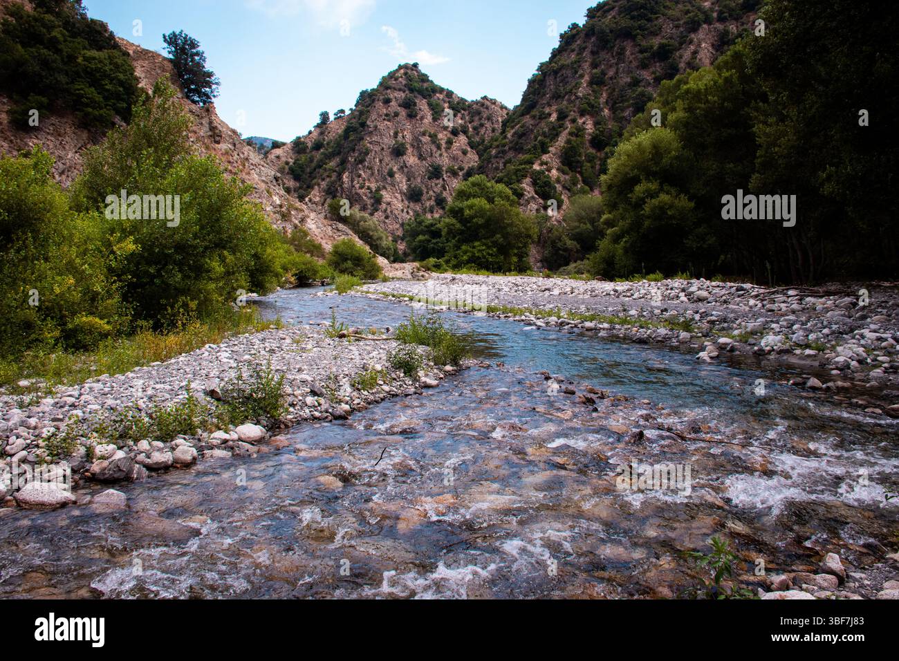 A peaceful mountain stream flows through rocky terrain, surrounded by ...