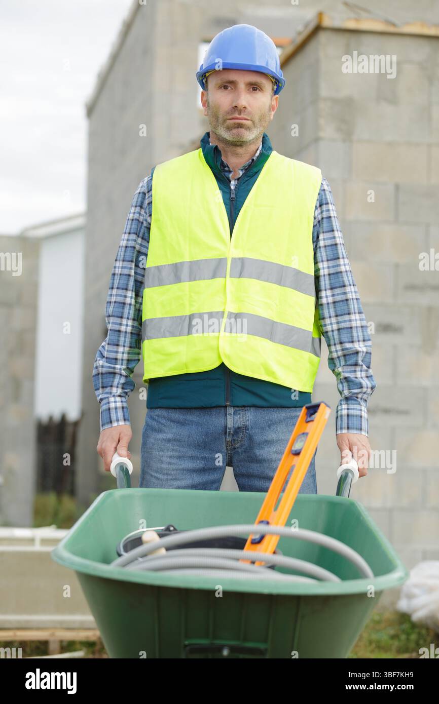 serious male construction worker pushing a wheelbarrow Stock Photo - Alamy