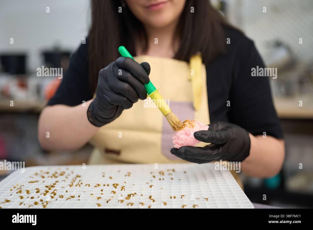 Candle maker applying gold leaf to pink flower-shaped candle Stock ...