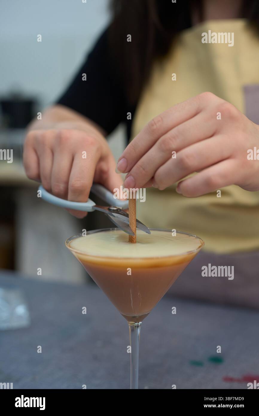 Candle maker cutting wick with scissors, preparing handmade candles ...