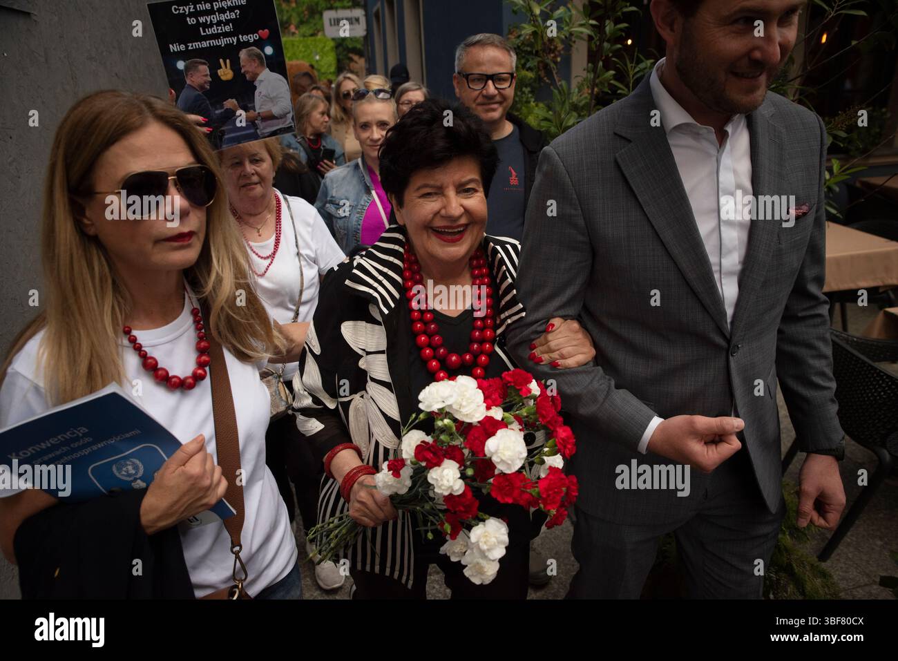 Joanna Senyszyn holding a bouquet of white and red flowers walks during ...