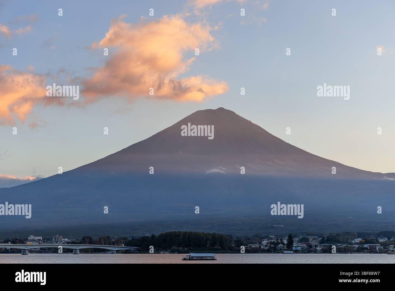 Golden sunset light highlights the peak of Mount Fuji, while the lower ...