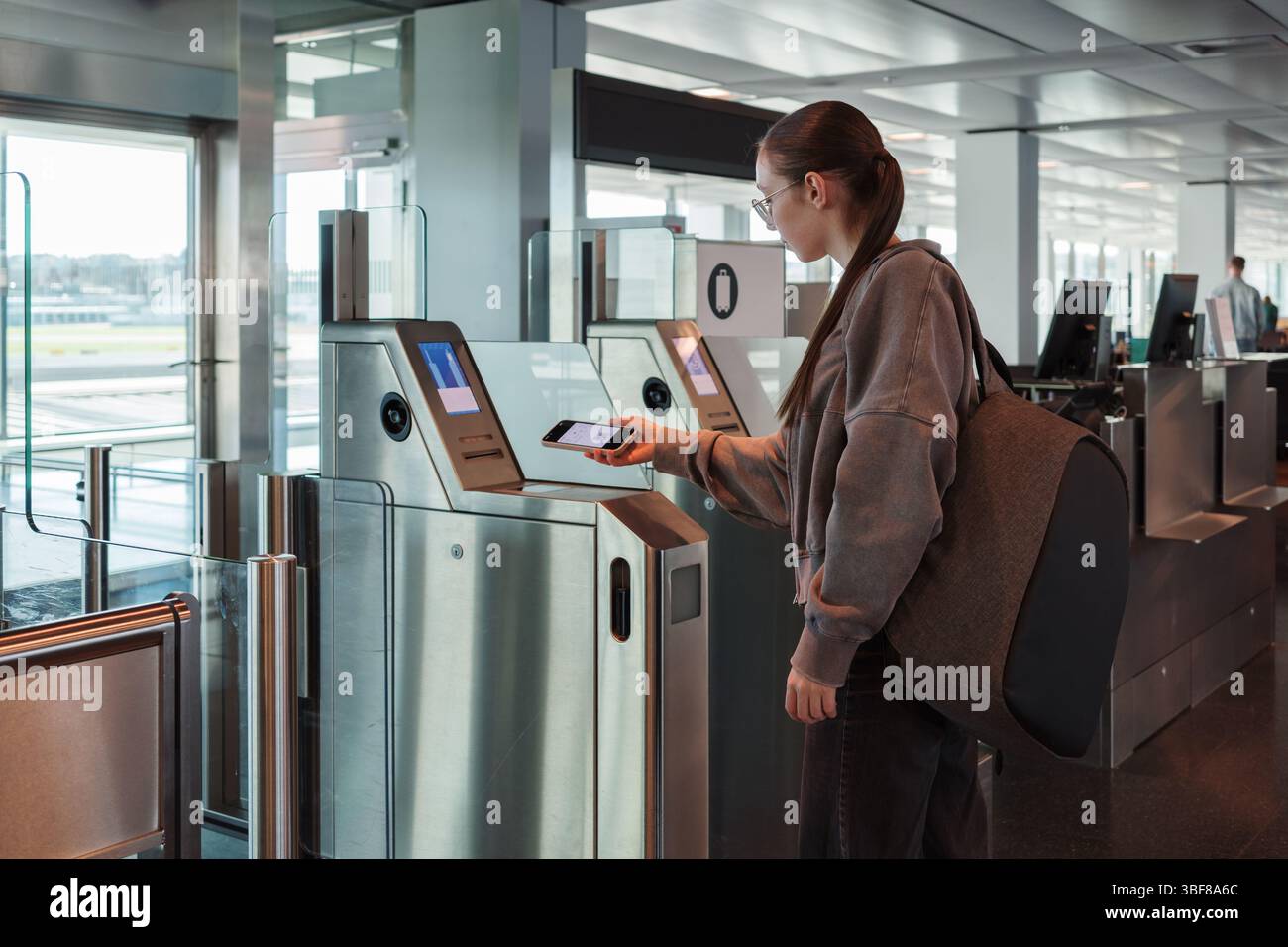 A young woman uses her smartphone to scan a boarding pass at an ...