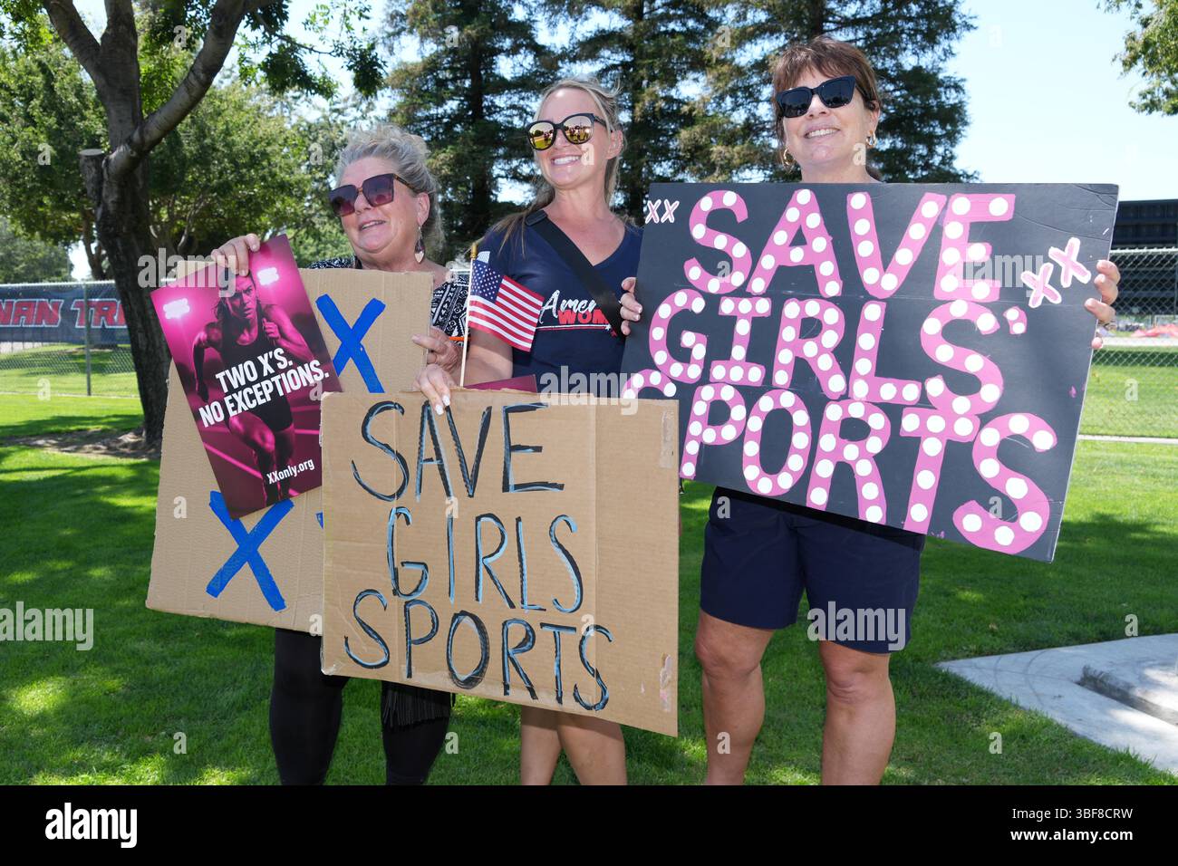 People hold Save Girls Sports signs in protest of transgender athlete ...