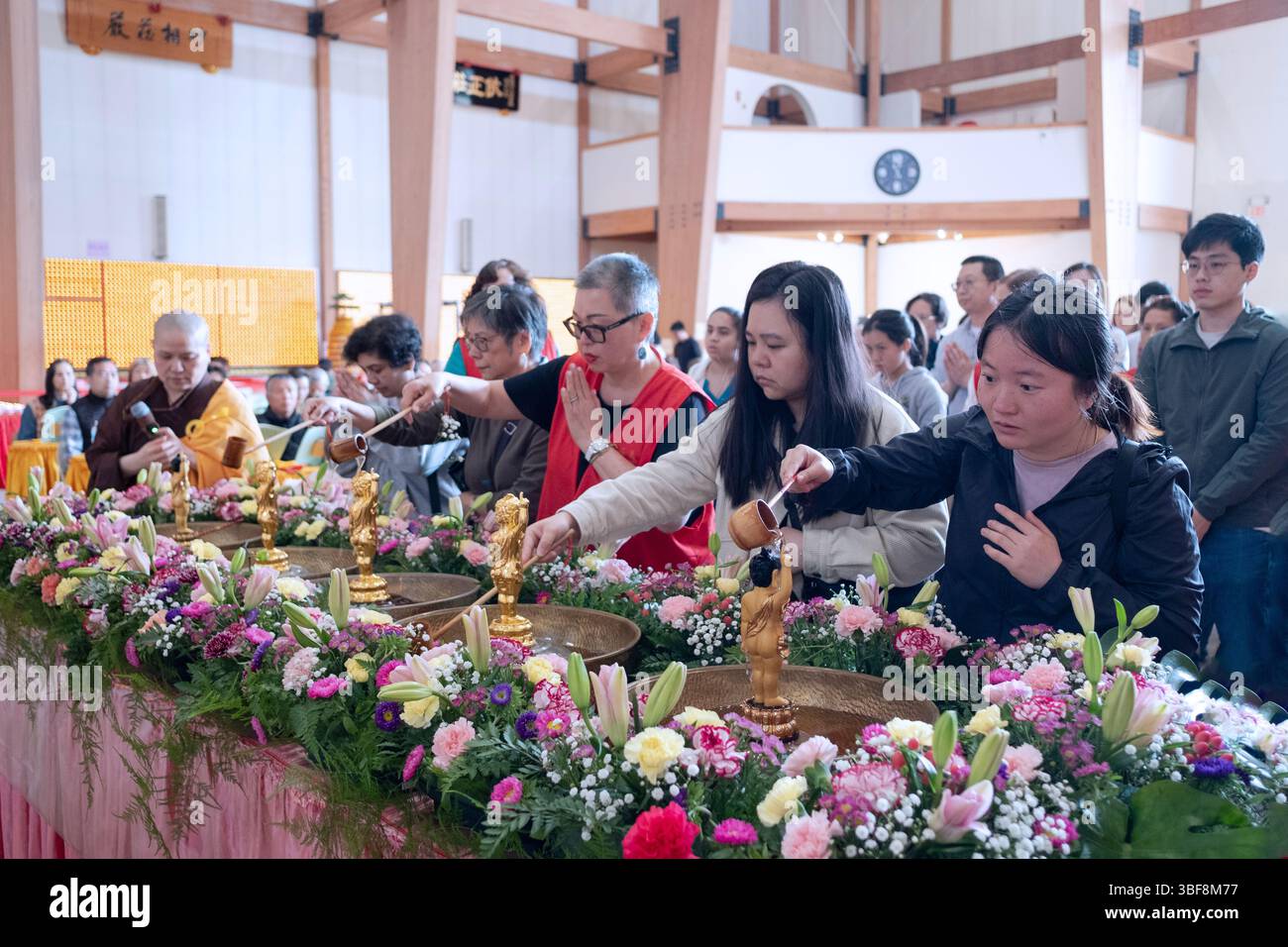 Worshippers pour water over the statue of the Baby Buddha as a symbol ...