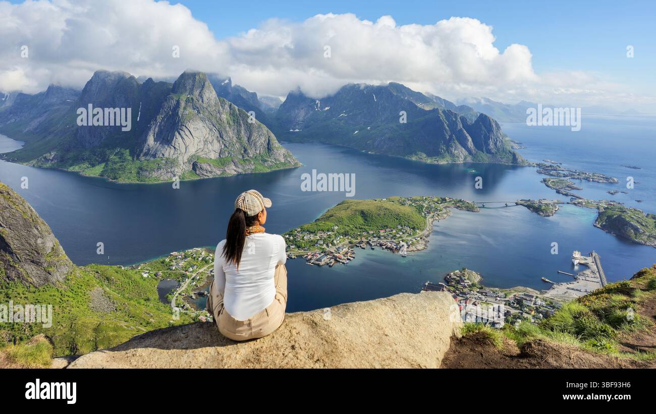 A traveler sits on a rocky ledge, gazing at the stunning panorama of ...