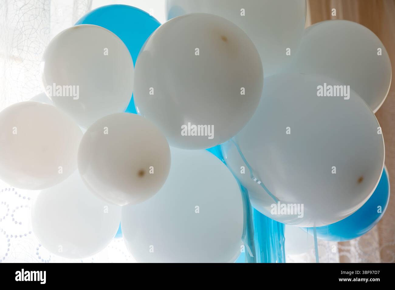 Clusters of white and light blue balloons are arranged in a bright ...