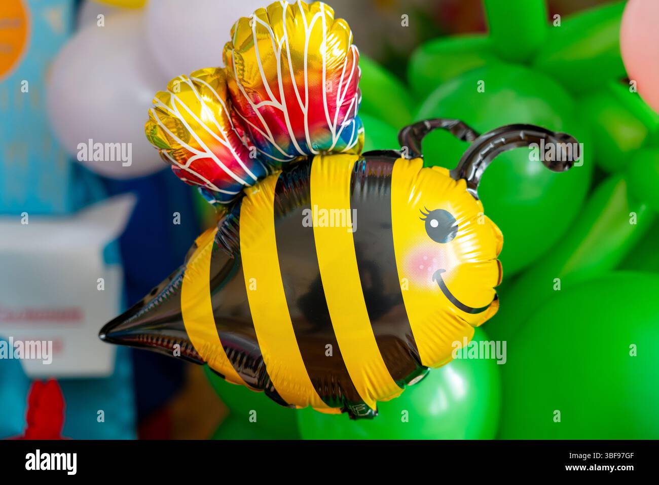 A cheerful bee balloon with black and yellow stripes floats among ...