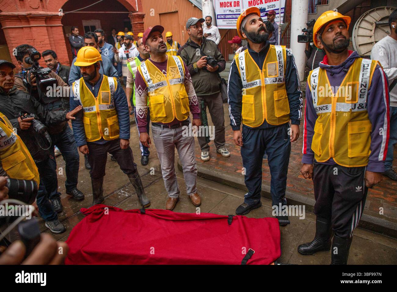 Civil Defence workers wait for a body as they participate in a civil defence mock drill inside ...