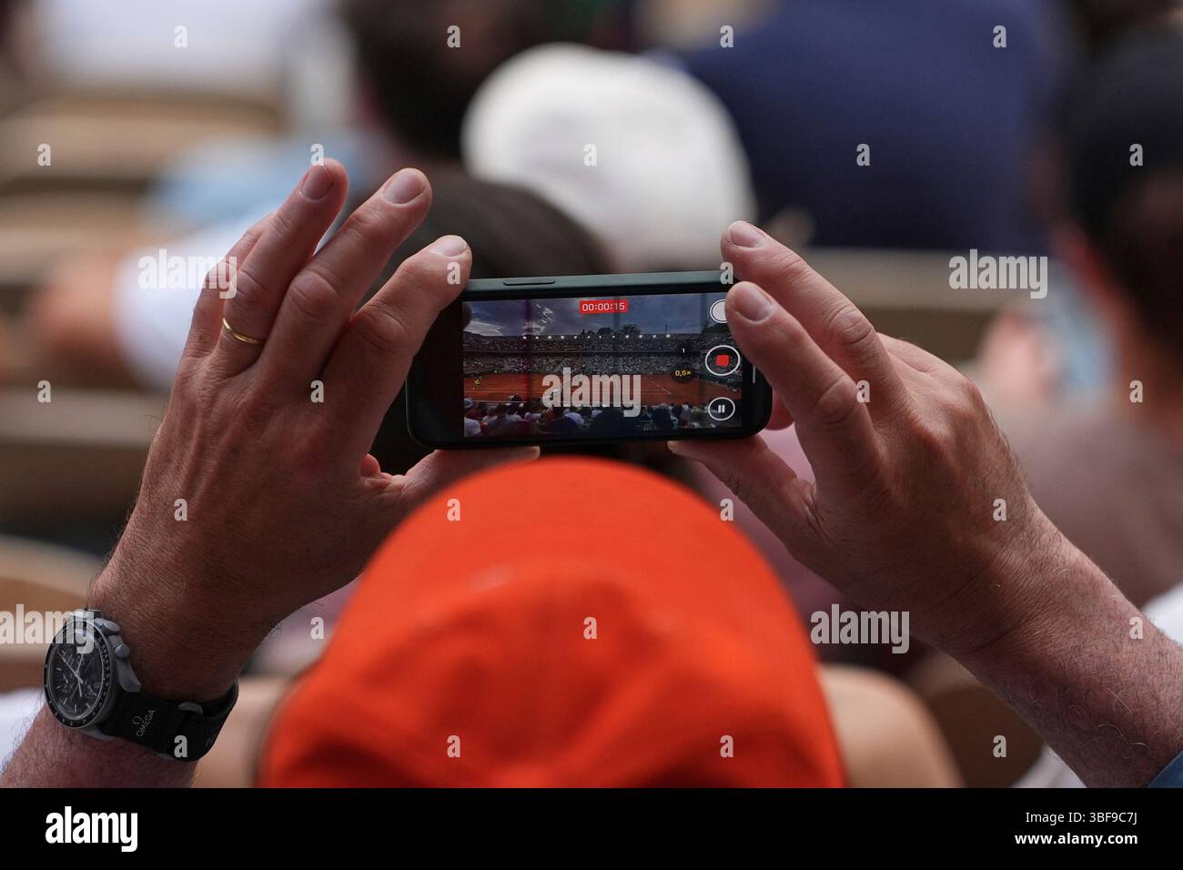A spectator takes photos of the third round match of the French Tennis ...