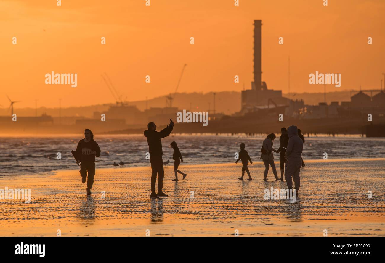 The setting sun seen from Brighton beach looking across Hove towards ...