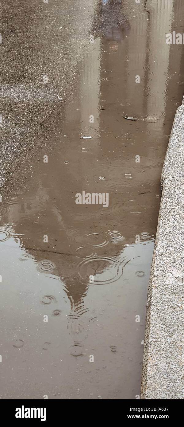 Rainy day city scene with architecture reflected in a puddle. People ...