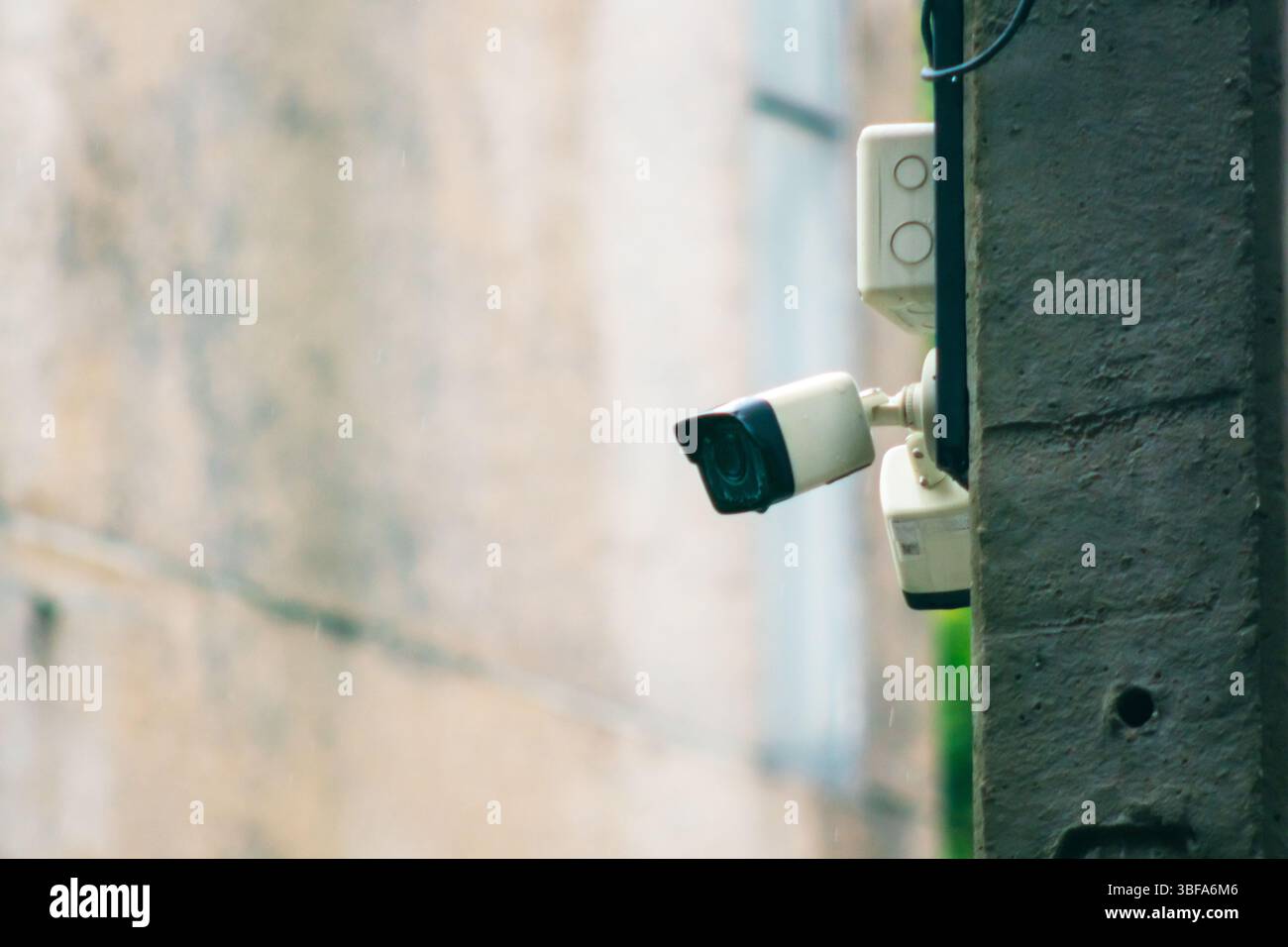 A security camera mounted on a concrete wall captures surveillance footage. This image ...
