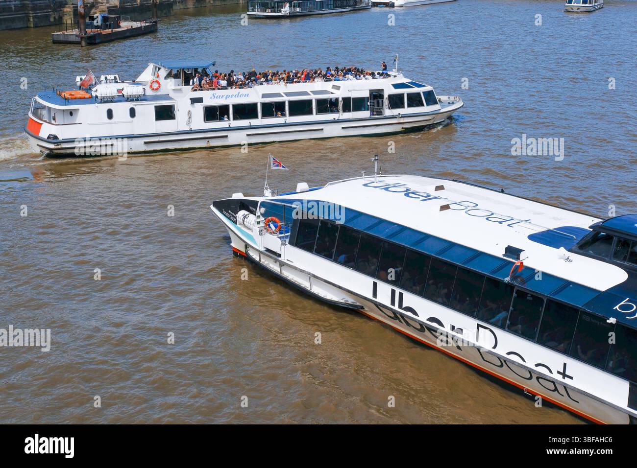 A tourist cruise boat and Uber Boat river ferry manoeuvre close to ...