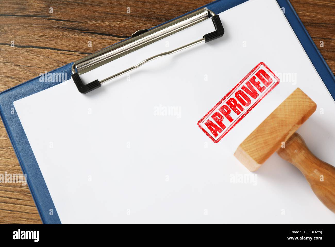 Sheet of paper with red stamp Approved and wooden stamp on table ...