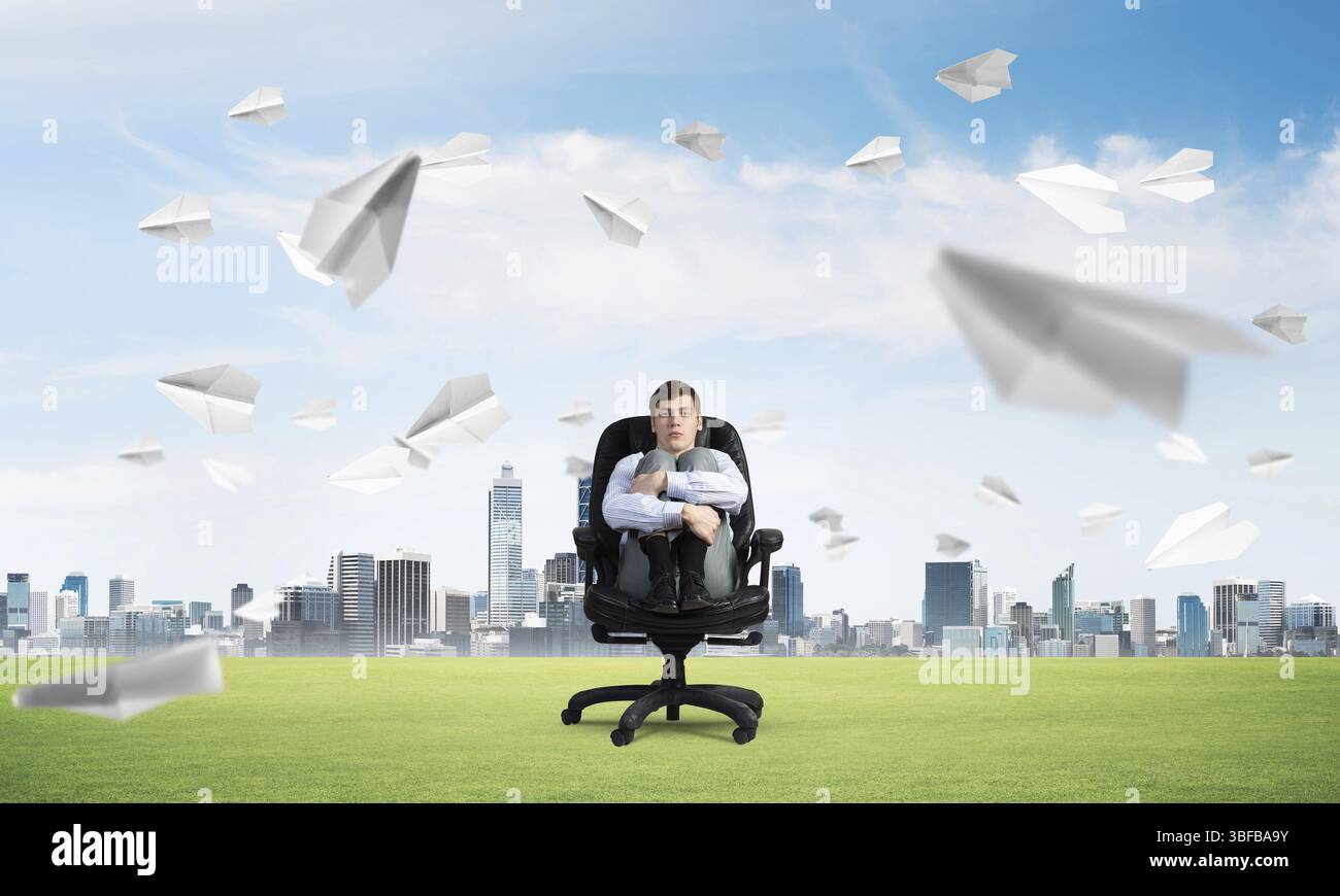 Scared businessman sitting on a chair with his hands clasped his knees ...