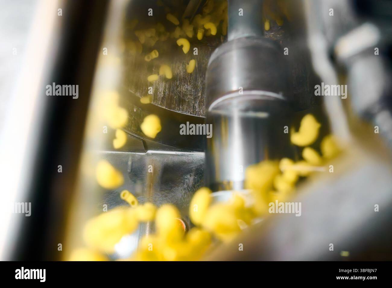 Pasta extrusion process showing yellow pasta shapes being formed and ...