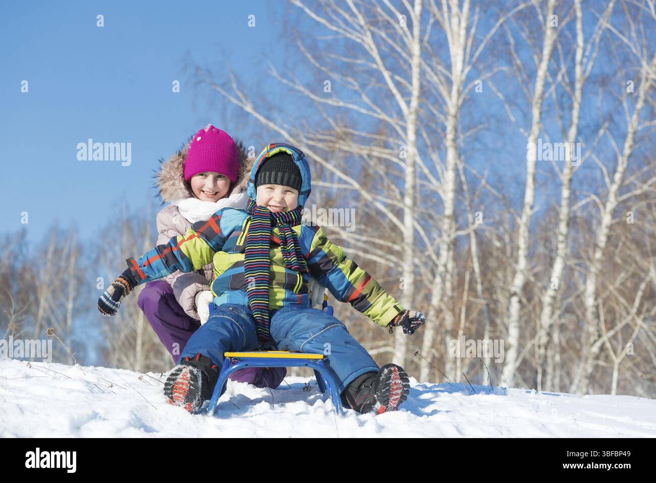 Two cute kids riding sled and having fun Stock Photo - Alamy