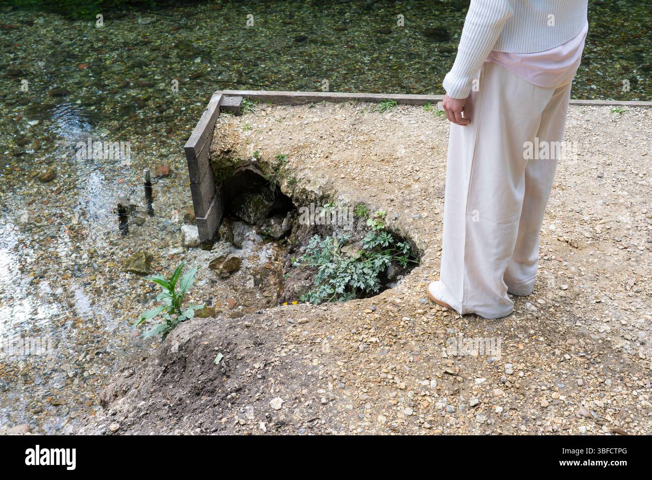 Woman looking at full bank scour occurring in the direction of flow ...