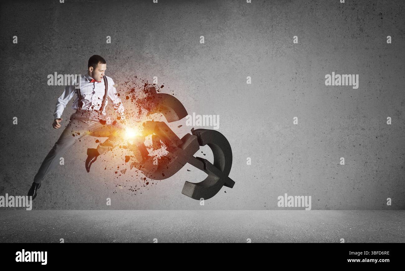 Young furious businessman jumping and crashing with kick stone dollar ...