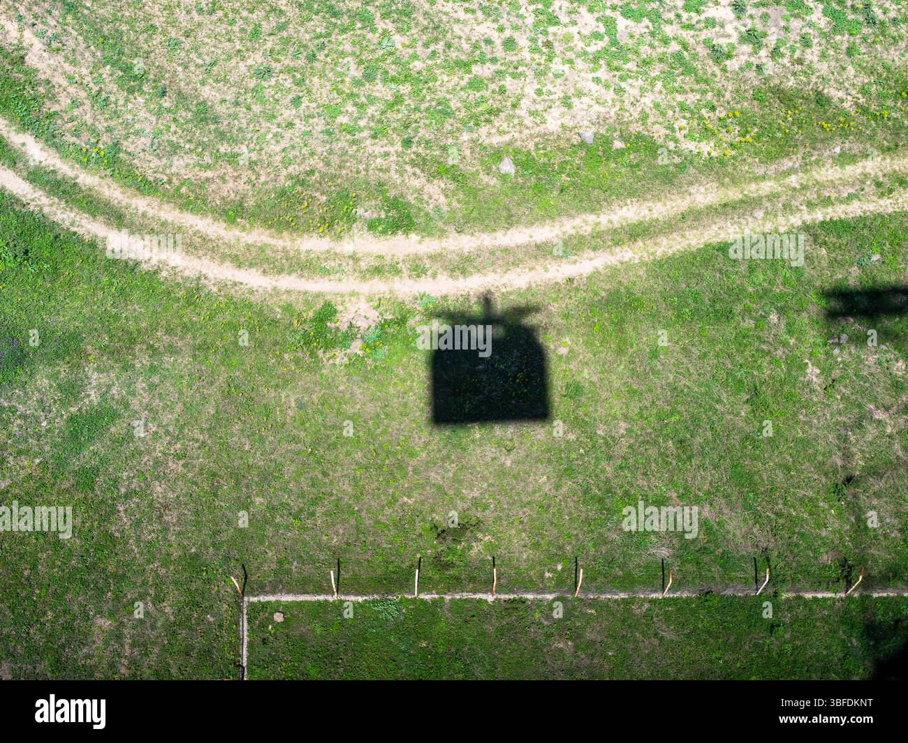 view of shadow of cable car cabin next to dirt road on mountain plateau ...