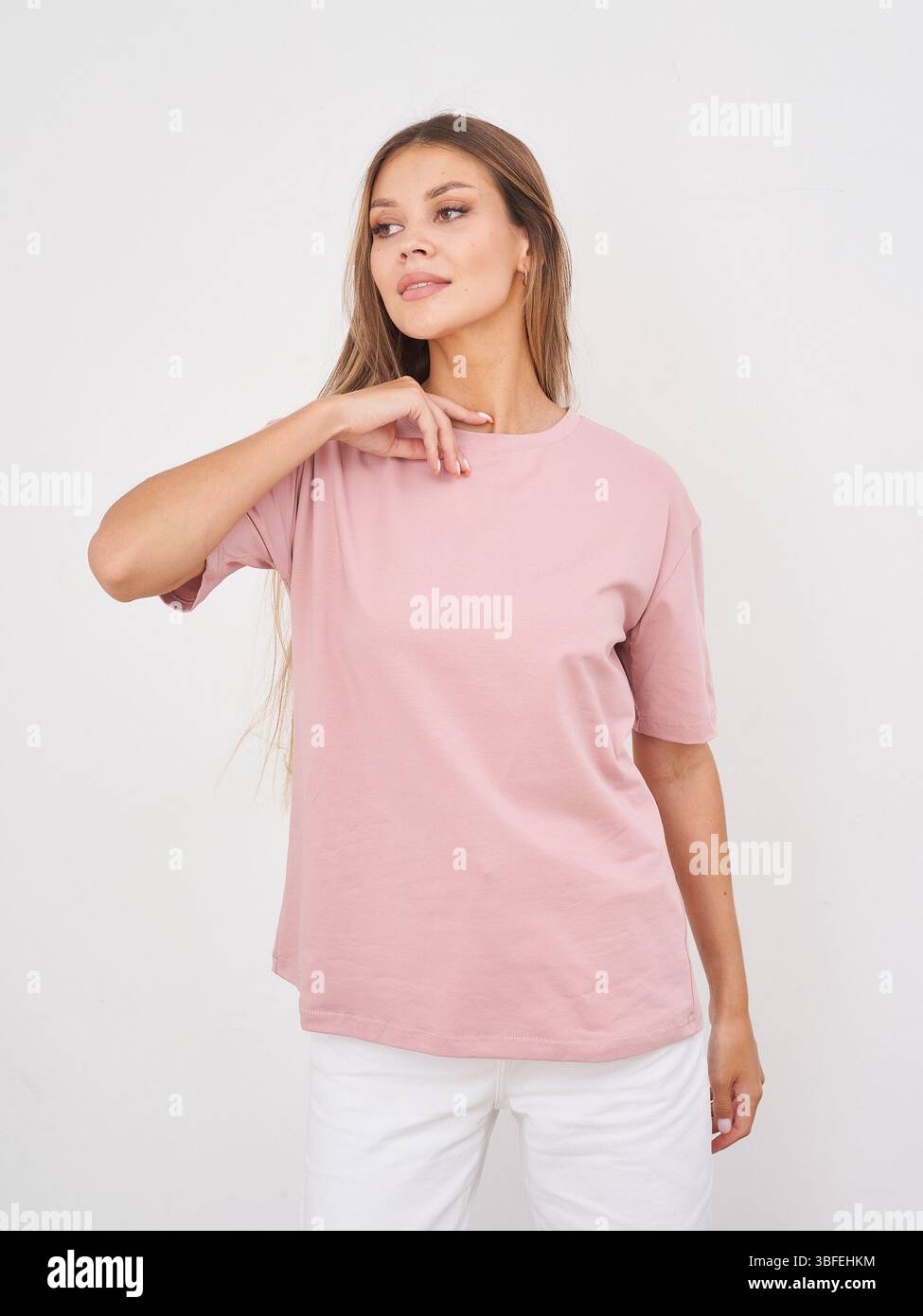 Model wearing pink t-shirt posing with elegance in a simple studio ...
