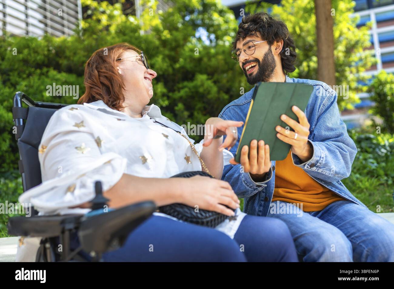 Happy woman with disability using tablet with her friend, modern ...