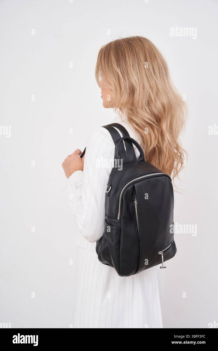 Blonde woman with wavy hair in a white outfit holding a stylish black ...