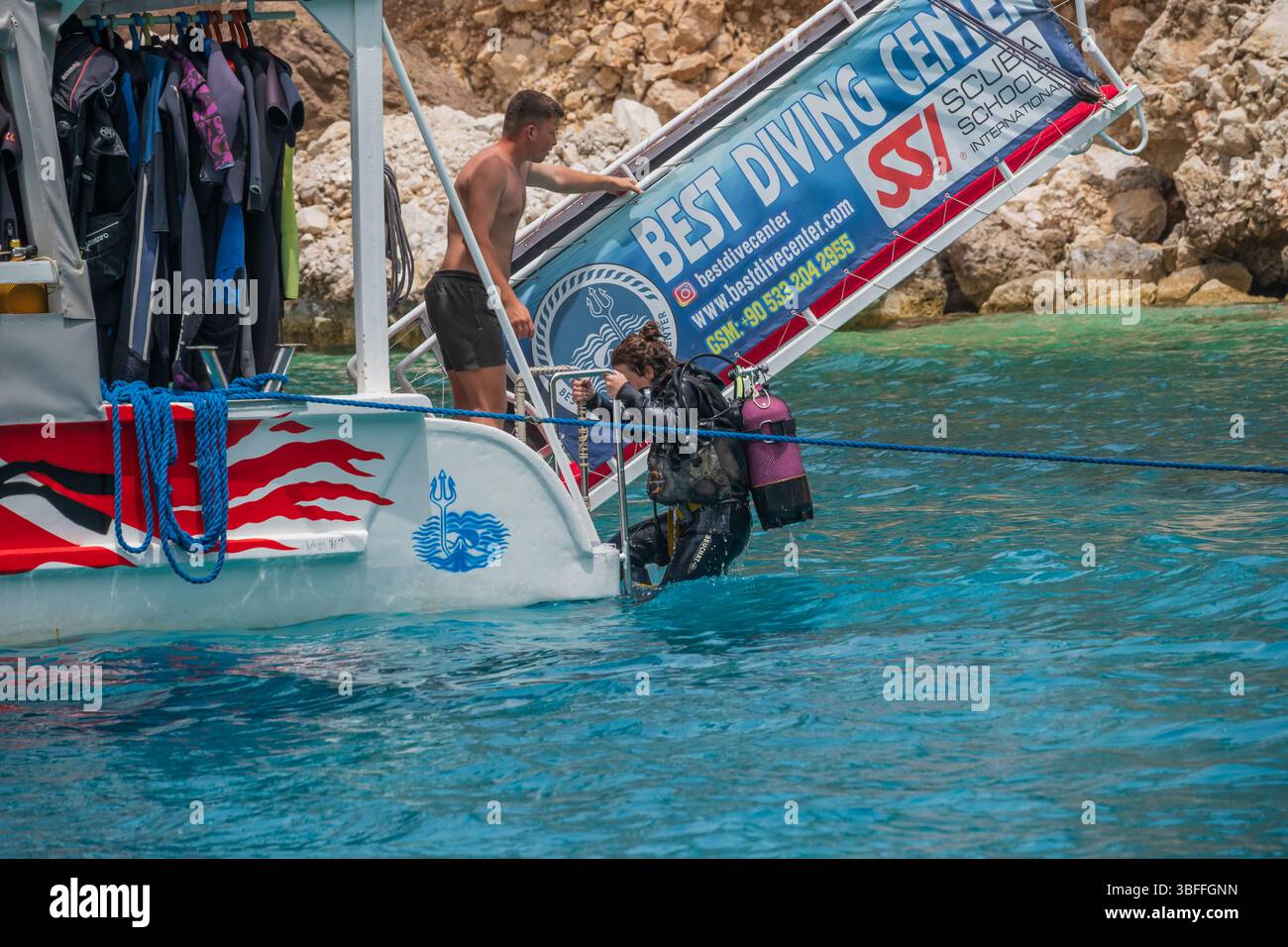 Scuba divers prepare to enter the crystal-clear turquoise waters from a ...