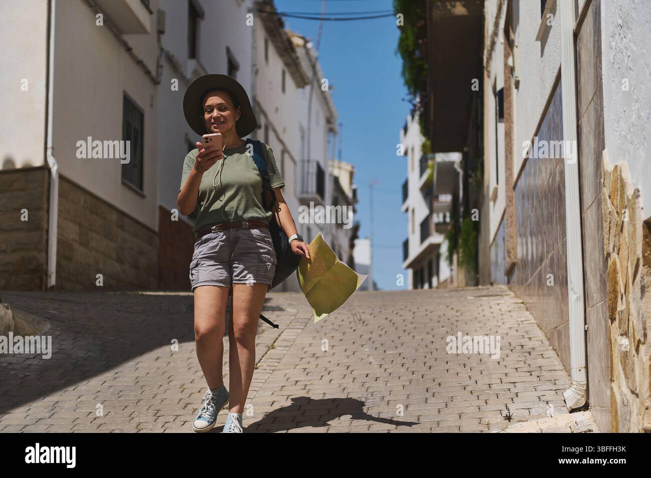 Adventurer walks in a charming Spanish cobblestone street, holding a ...