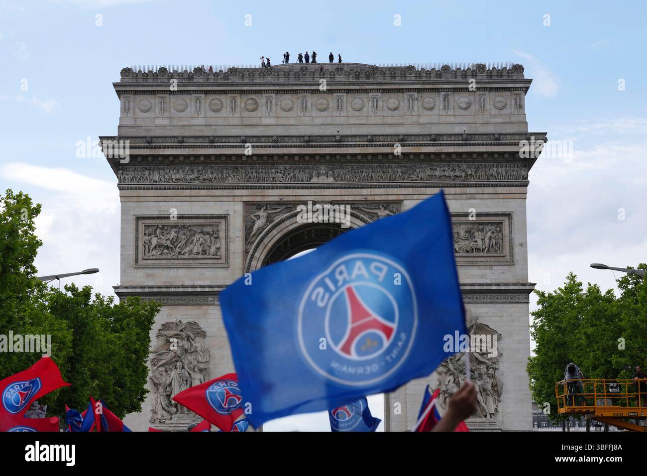 PSG supporters wave team flags during a parade in front of the Arc de ...