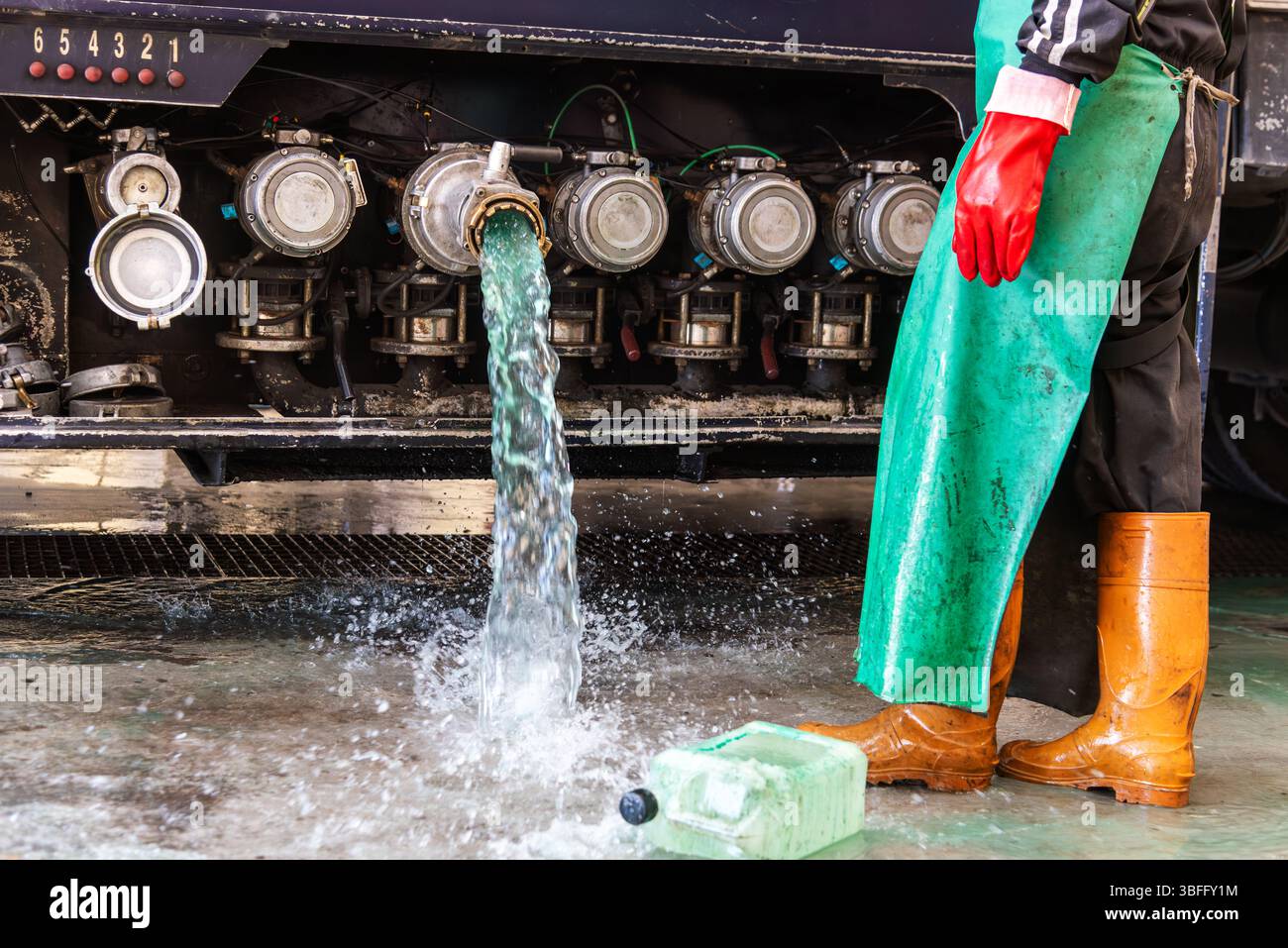 Operator at a tanker truck wash station discharging residue and water ...