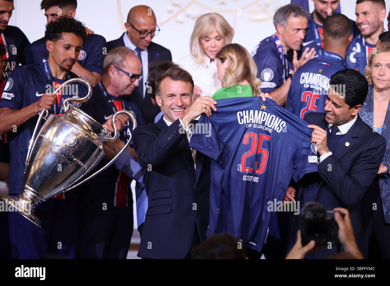 French President Emmanuel Macron, center left, holds a PSG jersey ...