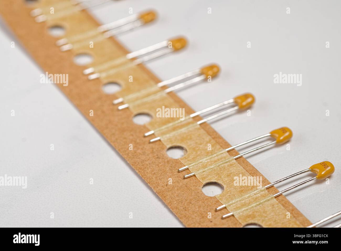 Multiple ceramic capacitors attached to a cardboard strip for automated ...