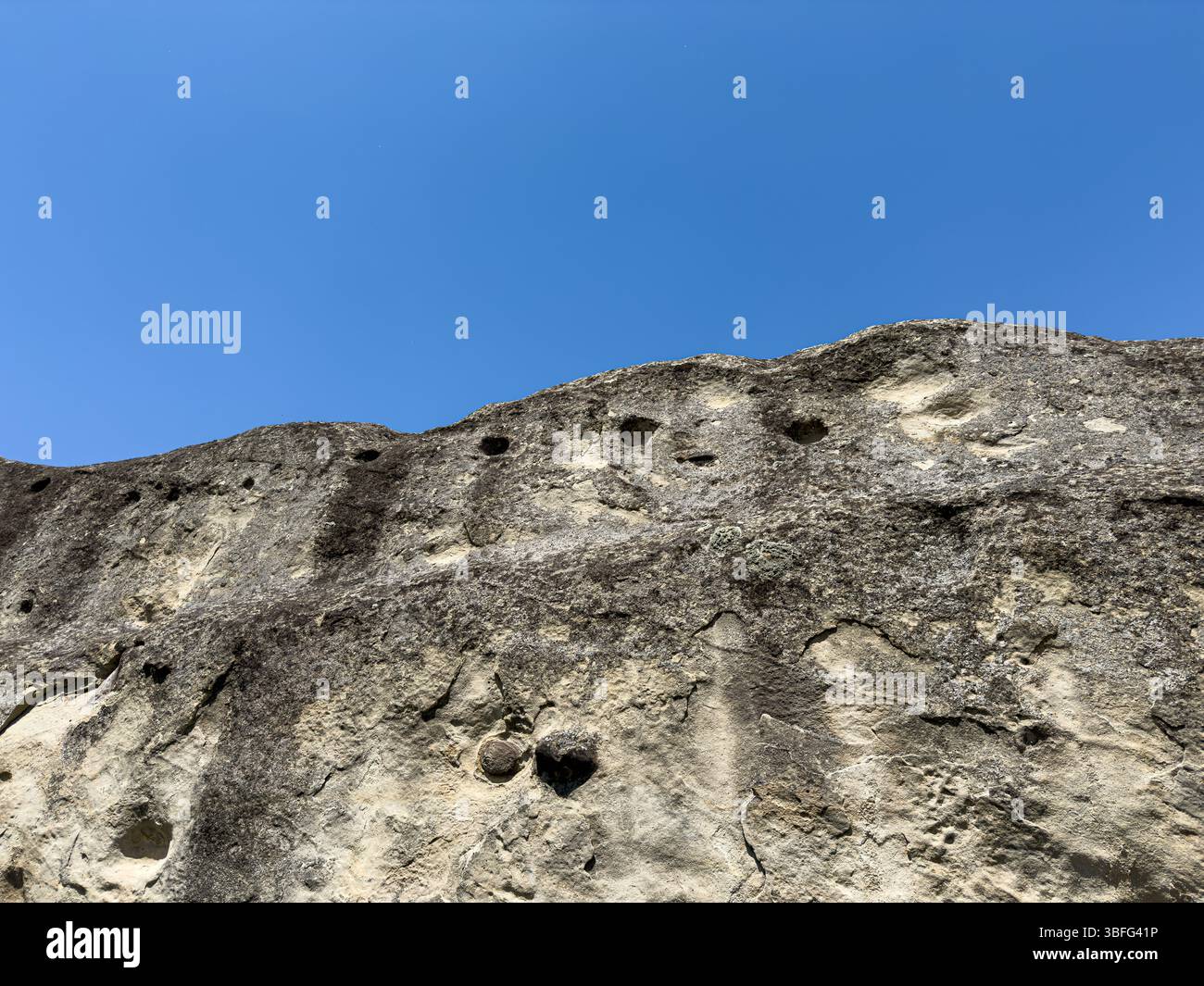 Rock wall with textured surface and erosion holes in cave city ...