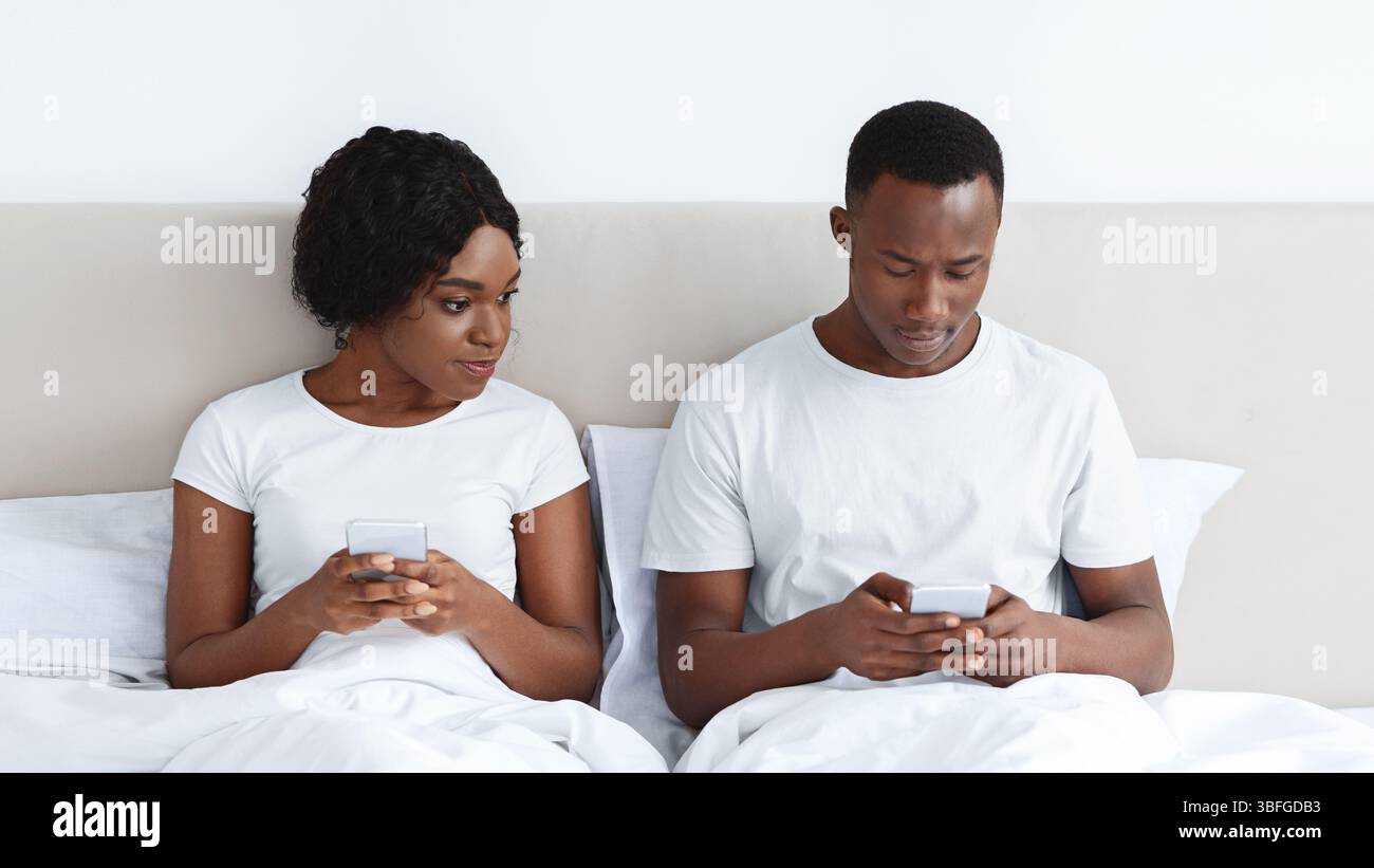 Young black woman eavesdropping on her boyfriend using mobile phone ...