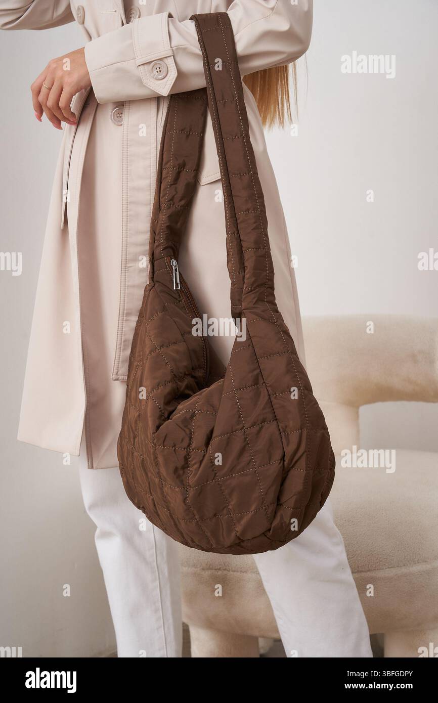 Beautiful brunette model showcasing a stylish brown handbag in a chic ...