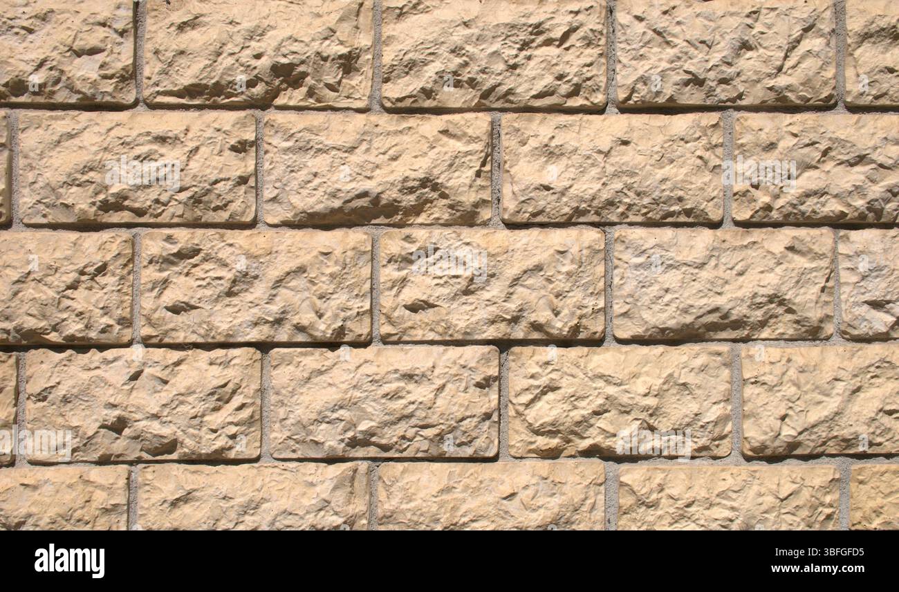 Close-up full-frame beige stone wall with rough, natural texture and ...