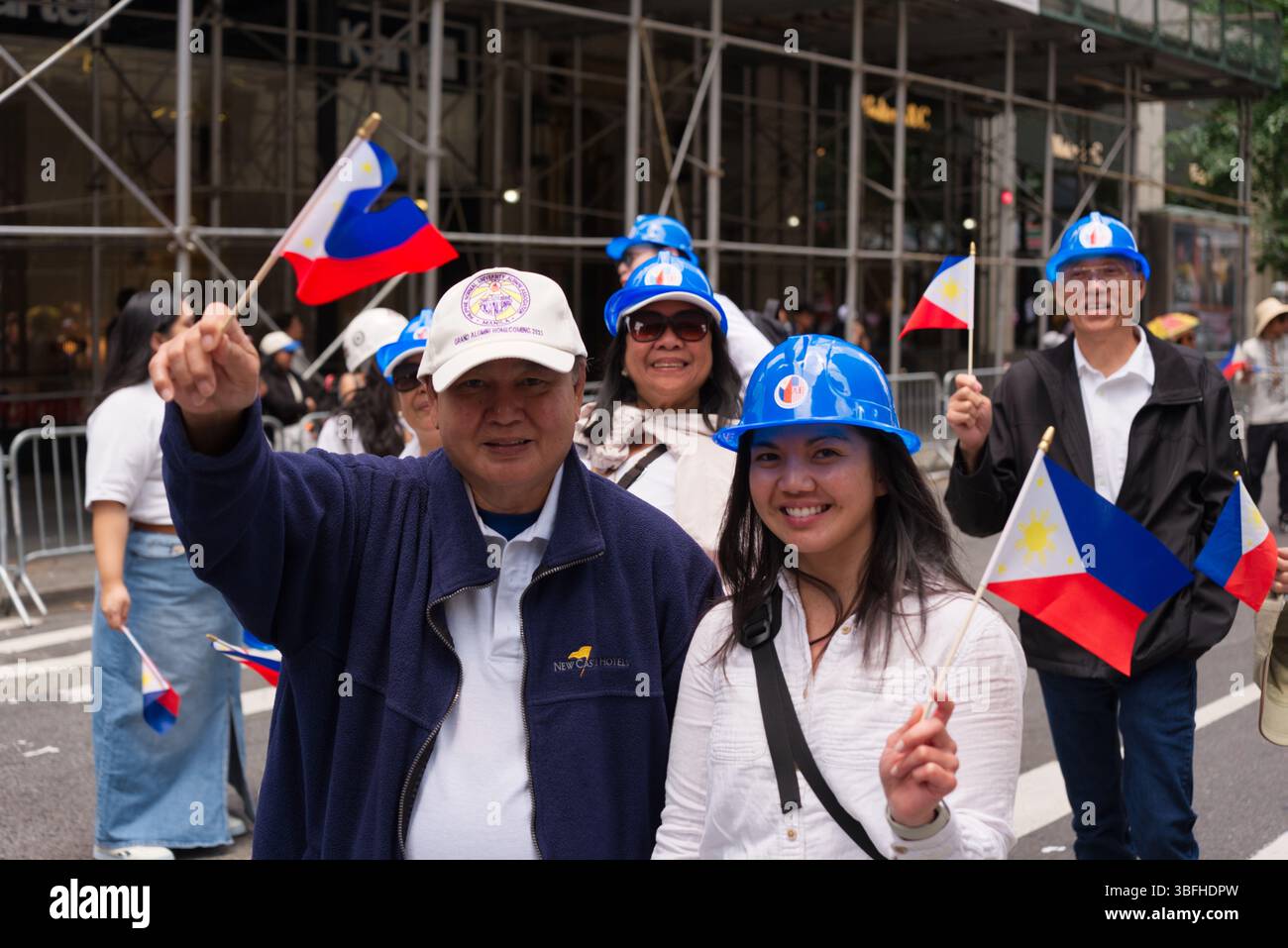 A group of Filipinos, many wearing blue hard hats and holding ...
