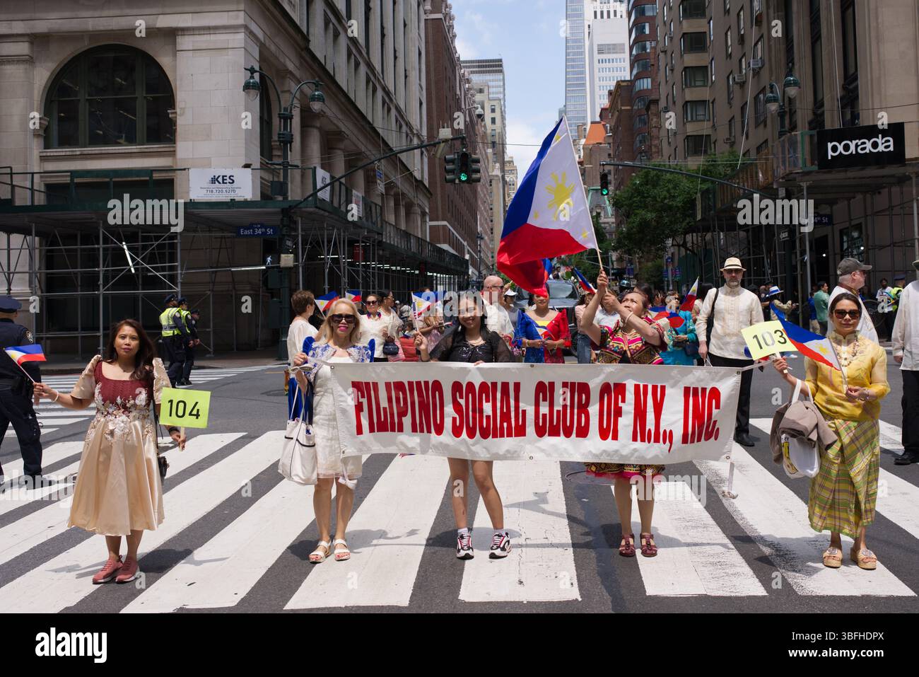 A group of Filipino people march in a parade, carrying a banner that ...