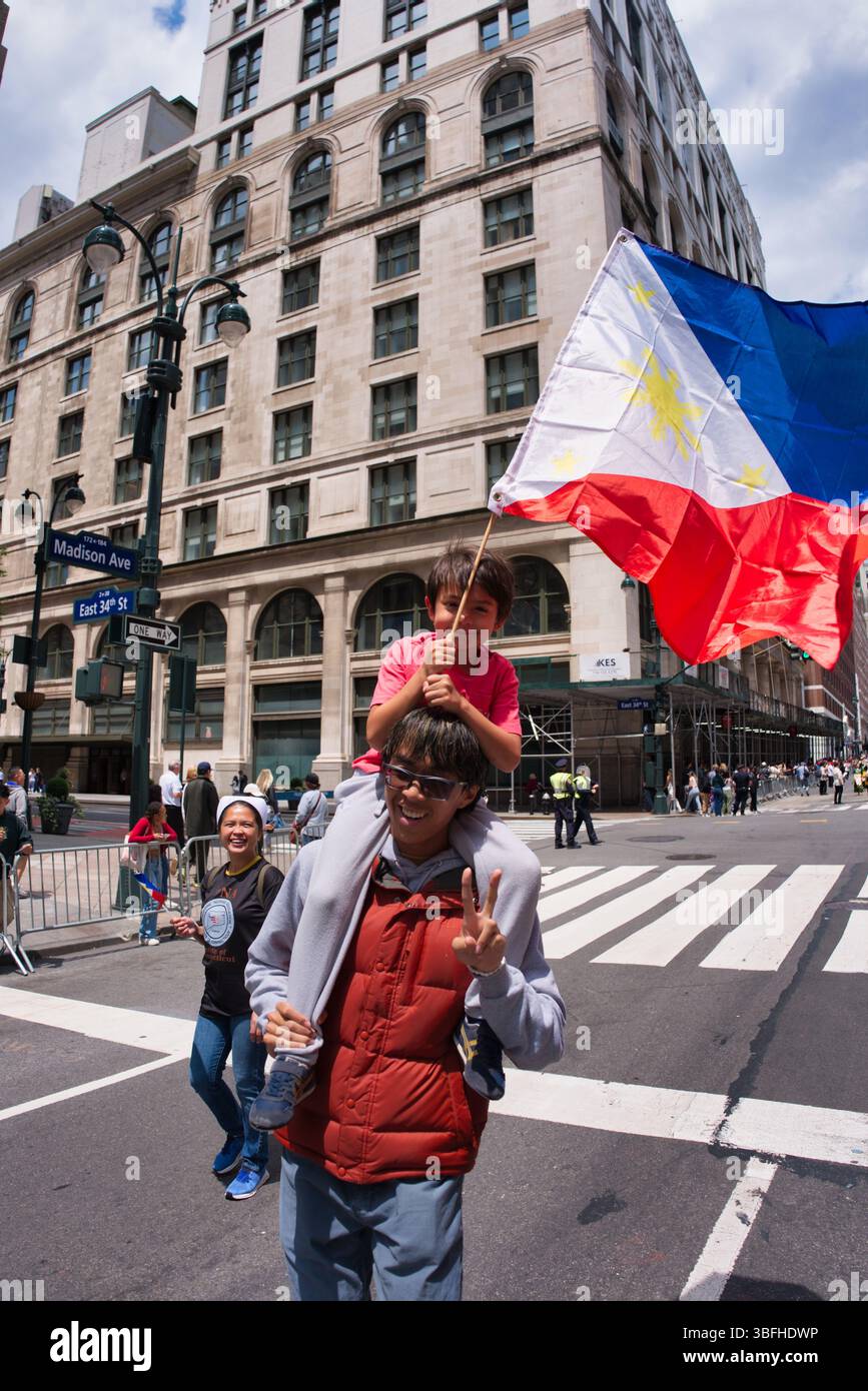 A man carries a child on his shoulders at a street parade. A Philippine ...